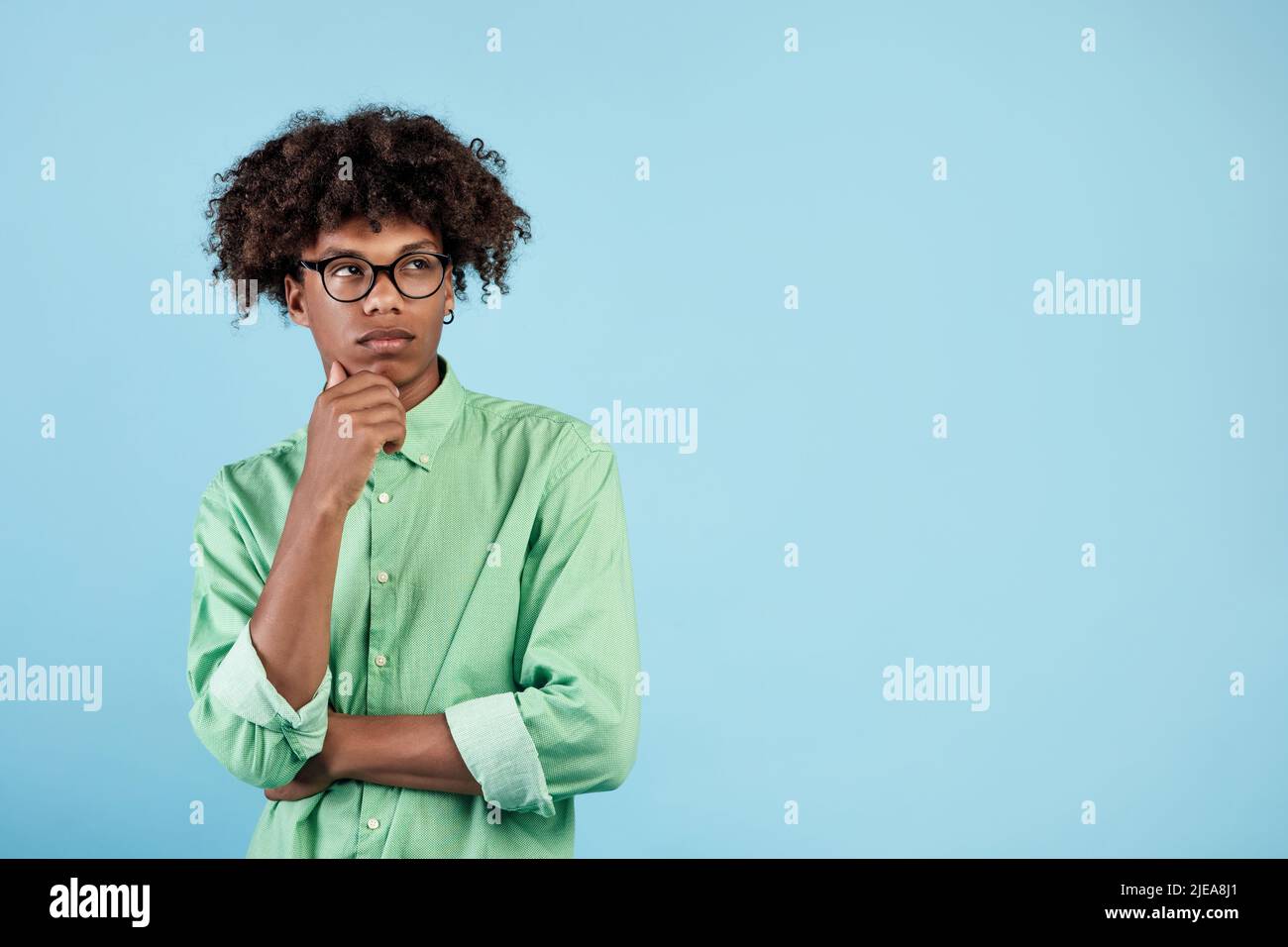 Pensive african american guy thinking over something on blue studio ...