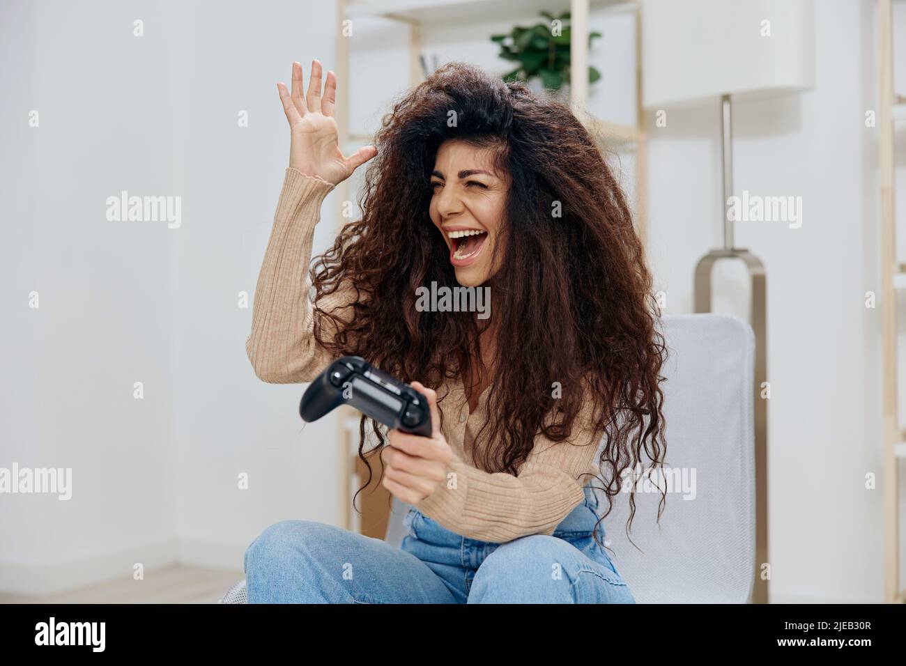 Overjoyed lucky tanned curly Latin winner lady hold with joystick ...