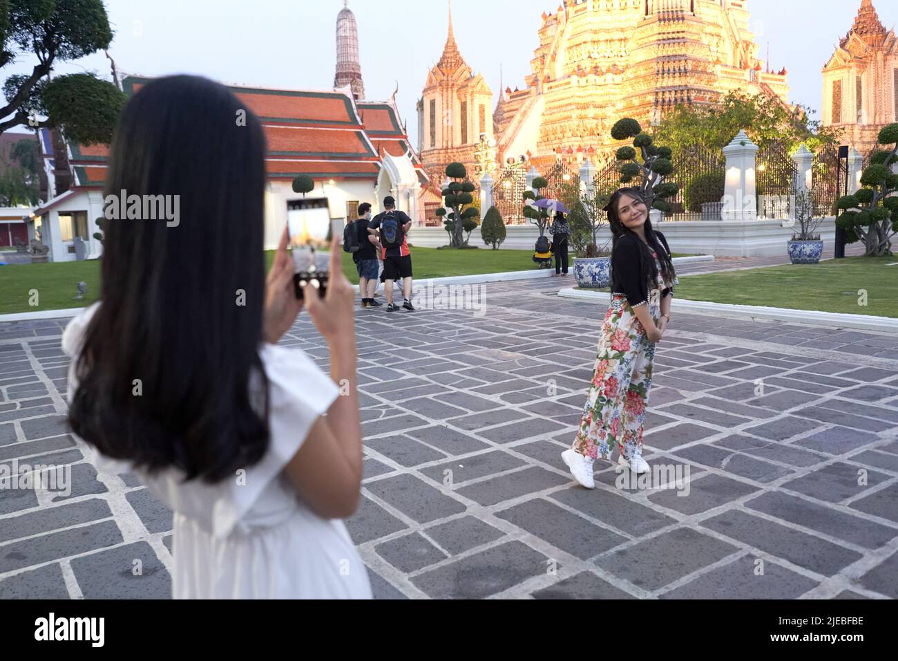 Woman taking a photo of a friend while visiting an ancient buddhist ...