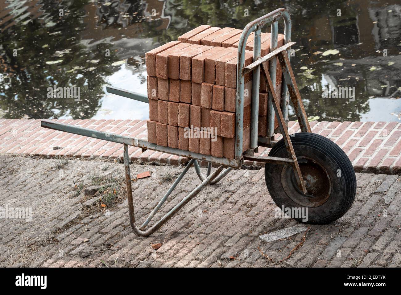 Rusty wheelbarrow with bricks, bricklayer tool isolated Stock Photo - Alamy