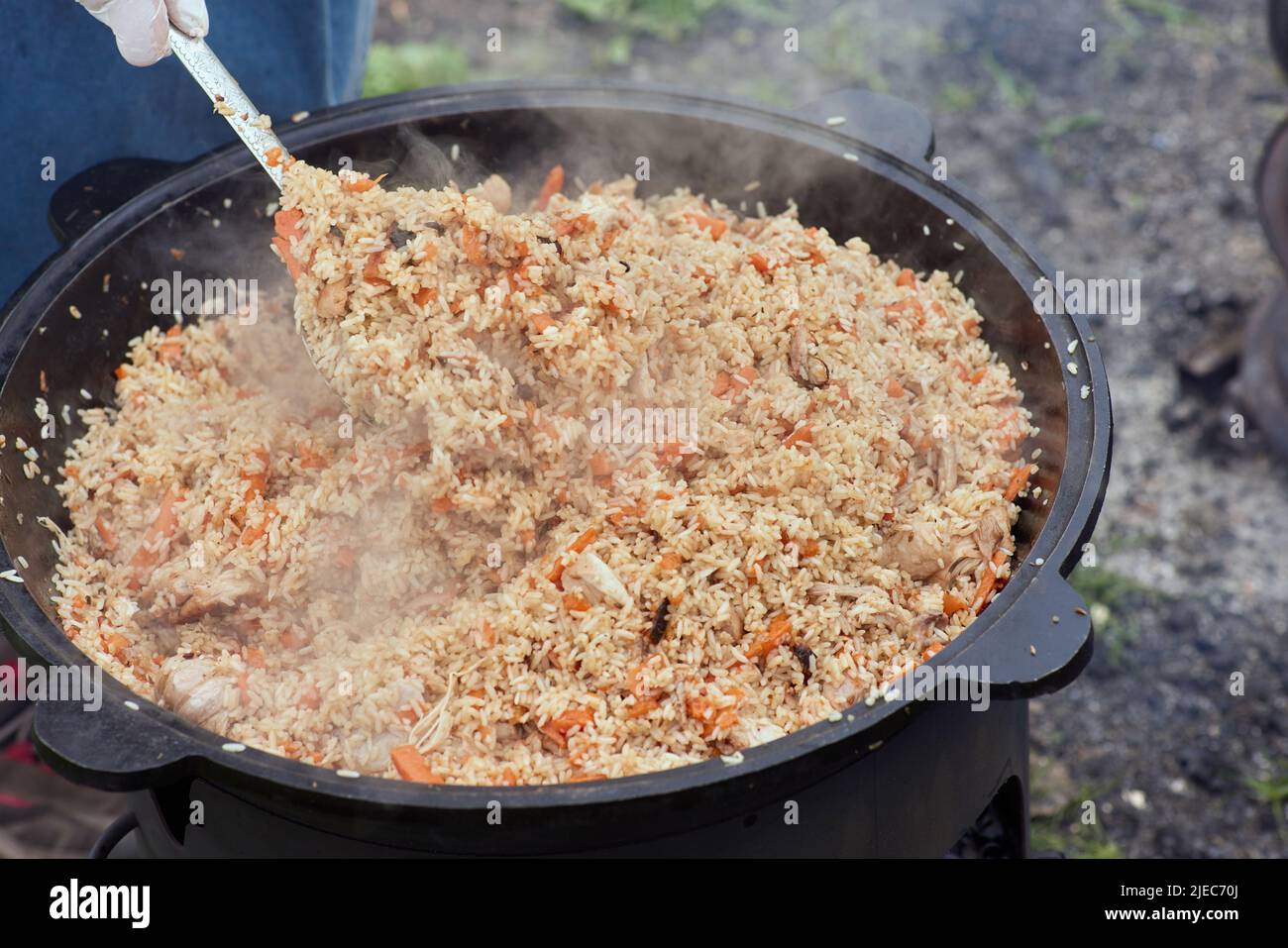 Cooking food or pilaf in a cauldron on fire. Cooking in cauldron on ...