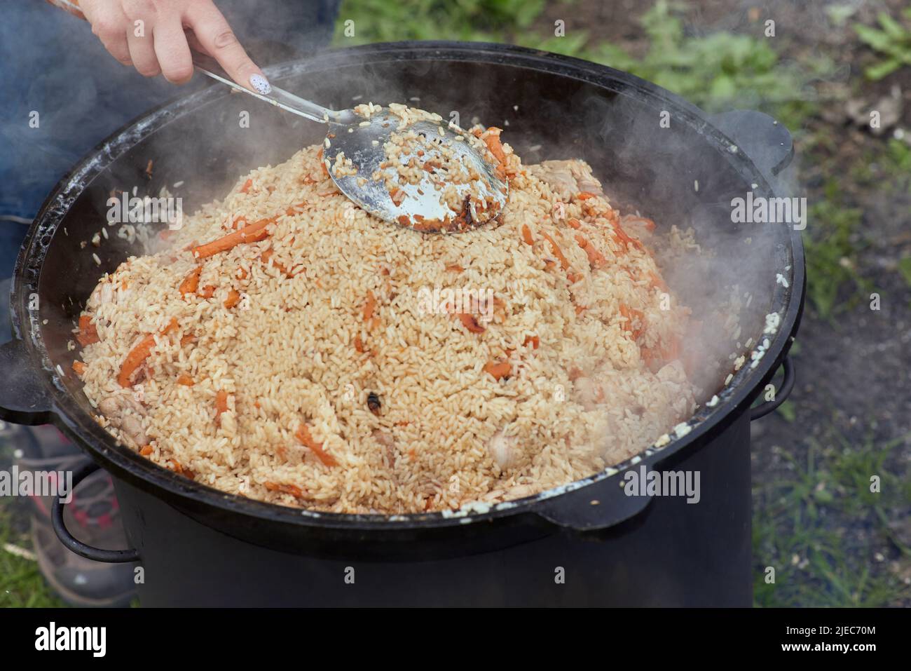 Cooking food or pilaf in a cauldron on fire. Cooking in cauldron on ...
