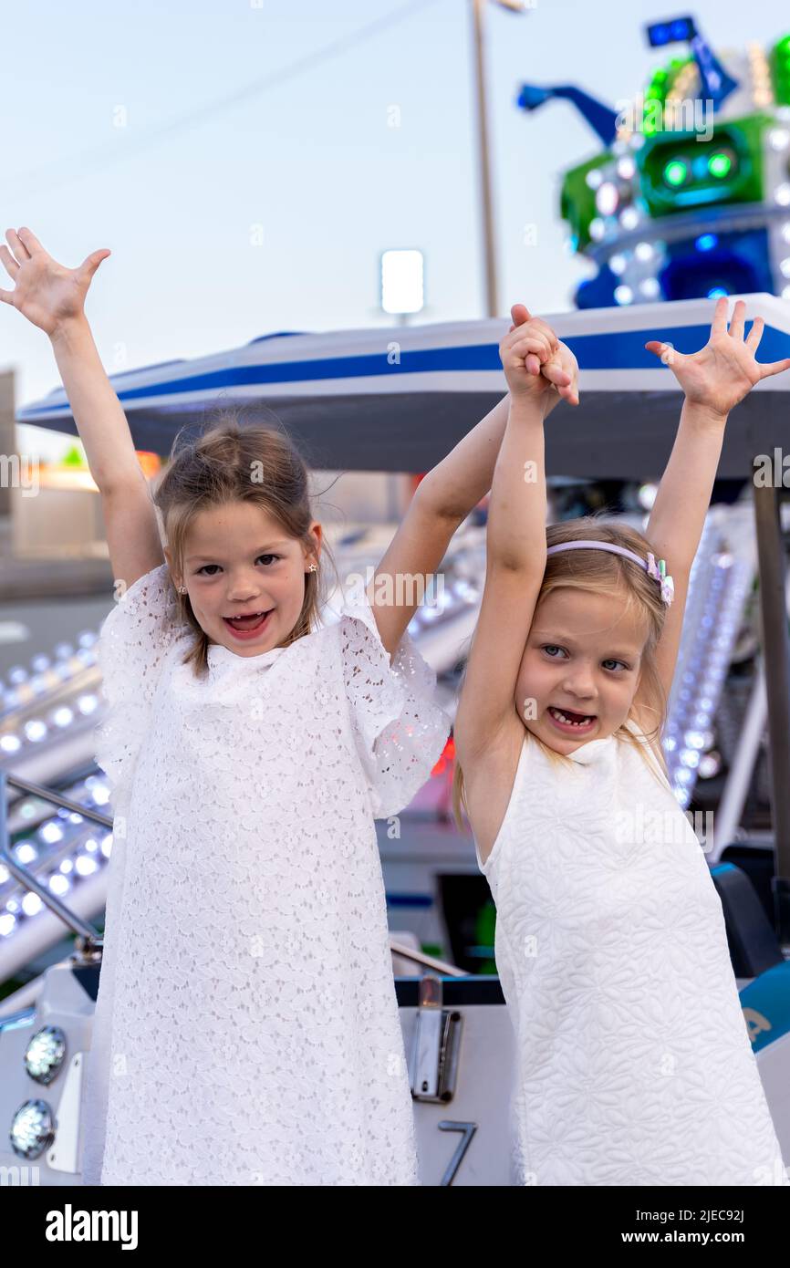 two happy sisters little girls having fun at the amusement park ...