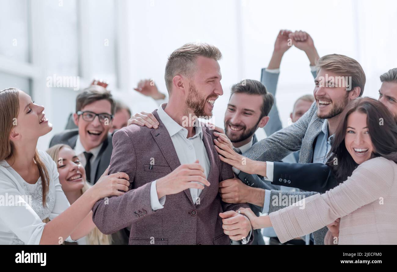 close up. cheerful company employees congratulating their colleague ...