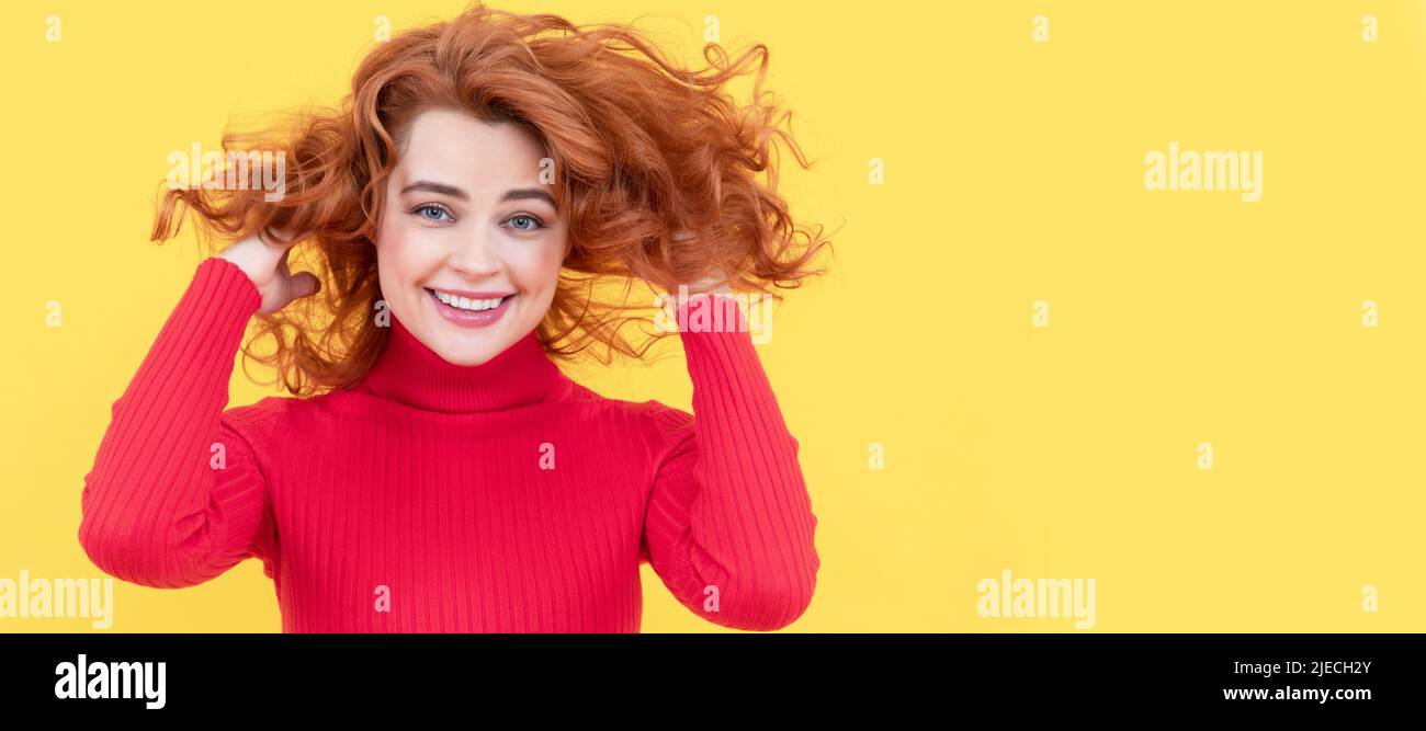 happy redhead woman with windy curly hair on yellow background ...