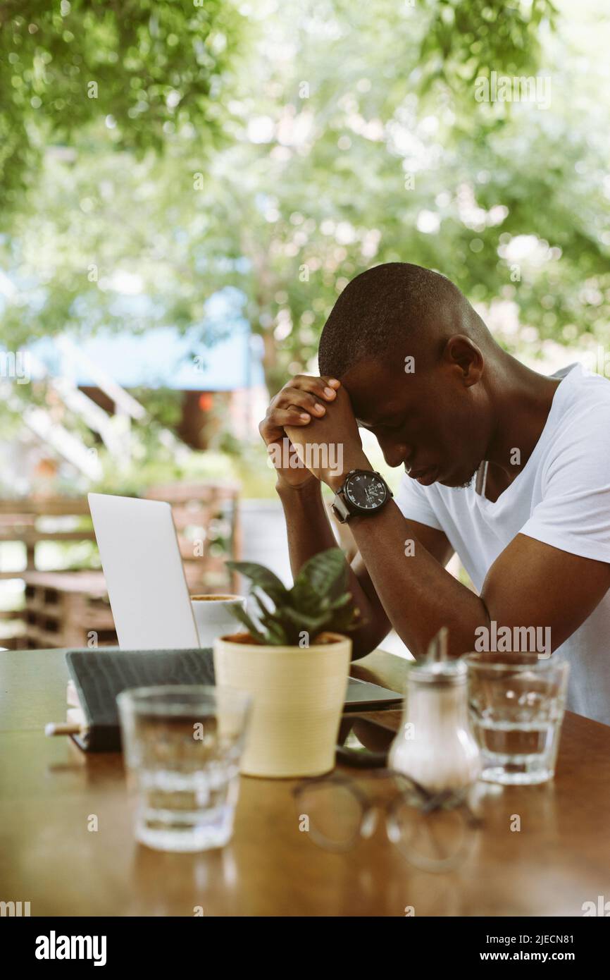 Vertical stressed dark skin man leaning his head on joint hands near ...