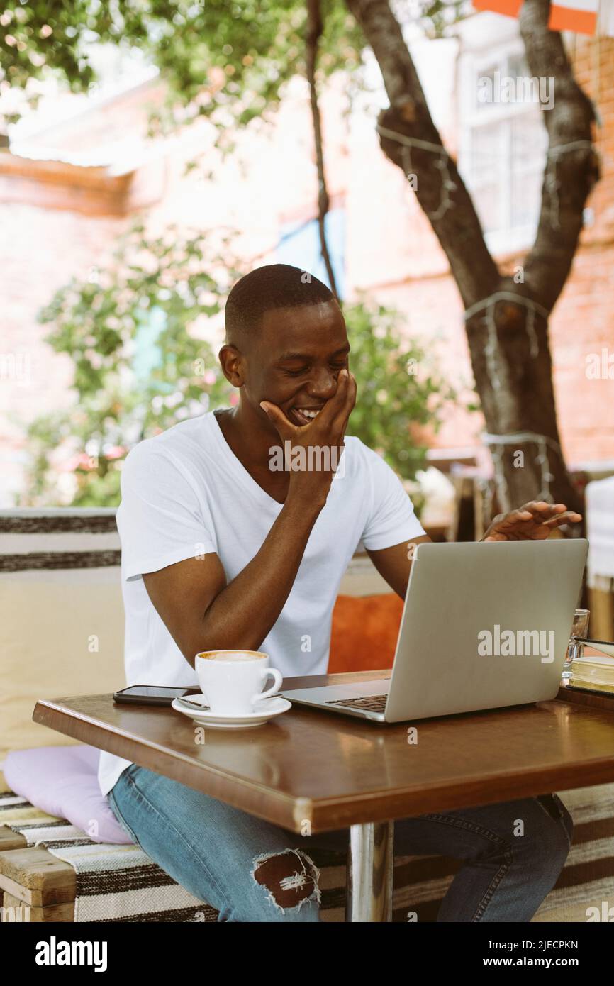 Smiling, laughing and cheerful african american man covering his face ...