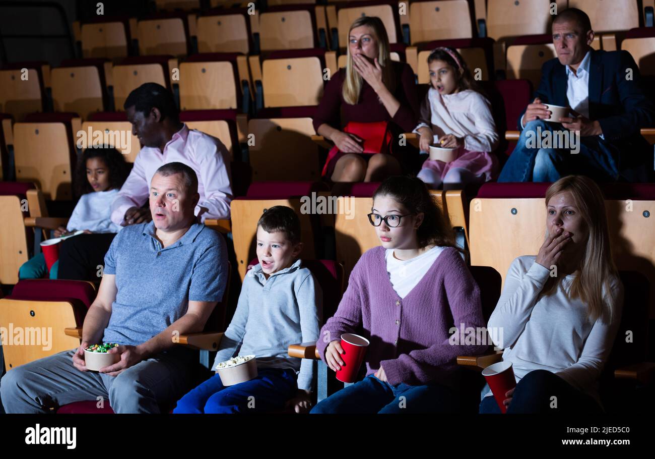 Spectators eating popcorn and watching horror movie in cinema Stock ...