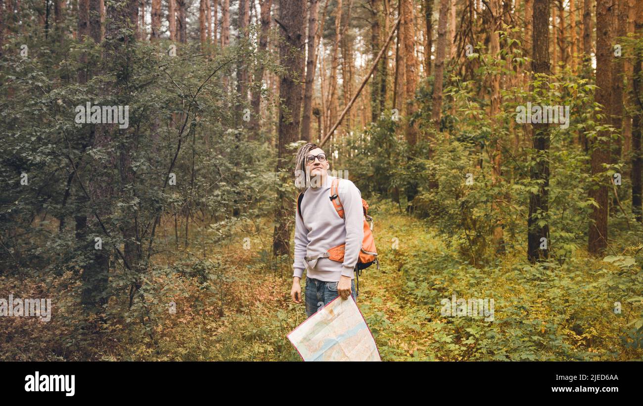 A traveling man with dreadlocks with a map in the forest. A male ...