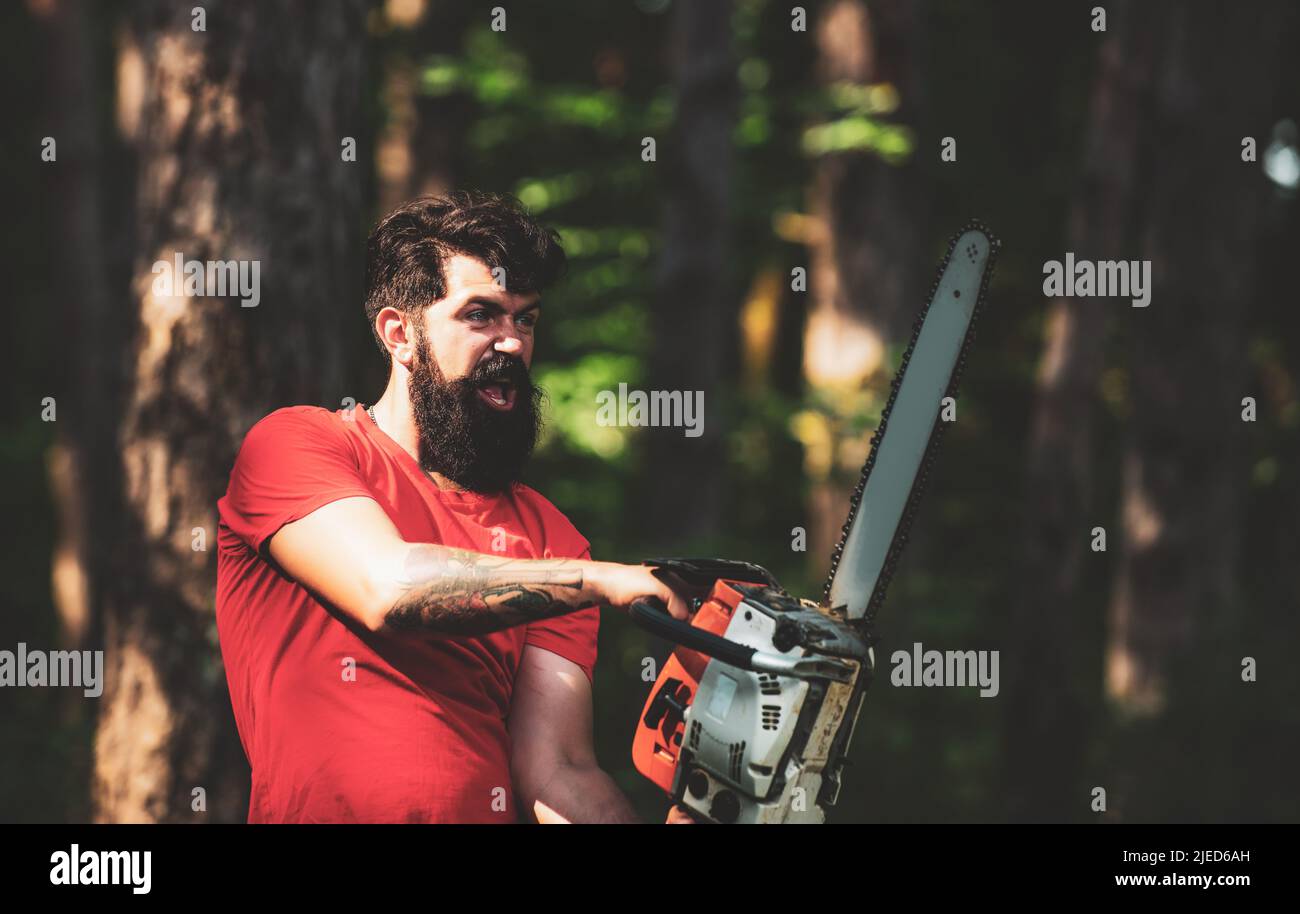 Lumberjack on serious face carries chainsaw. Woodcutter with chainsaw ...