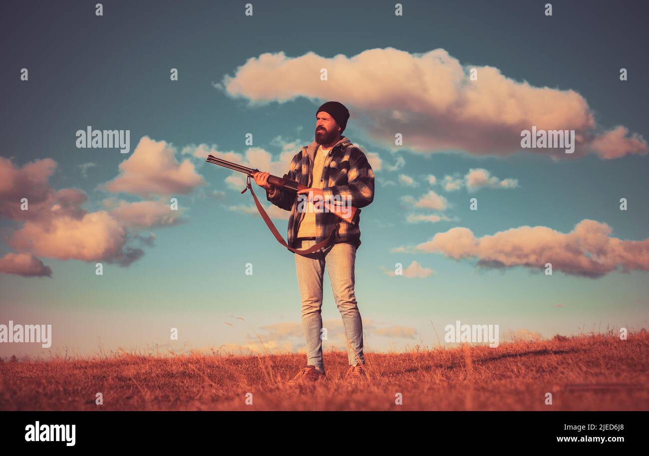 Bearded hunter man holding gun and walking in forest. Hunter with ...