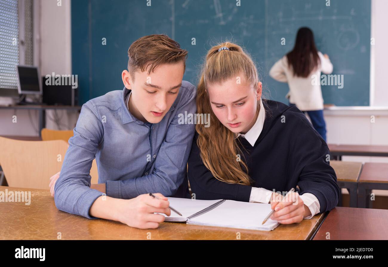 Teenager explaining girl study material Stock Photo - Alamy