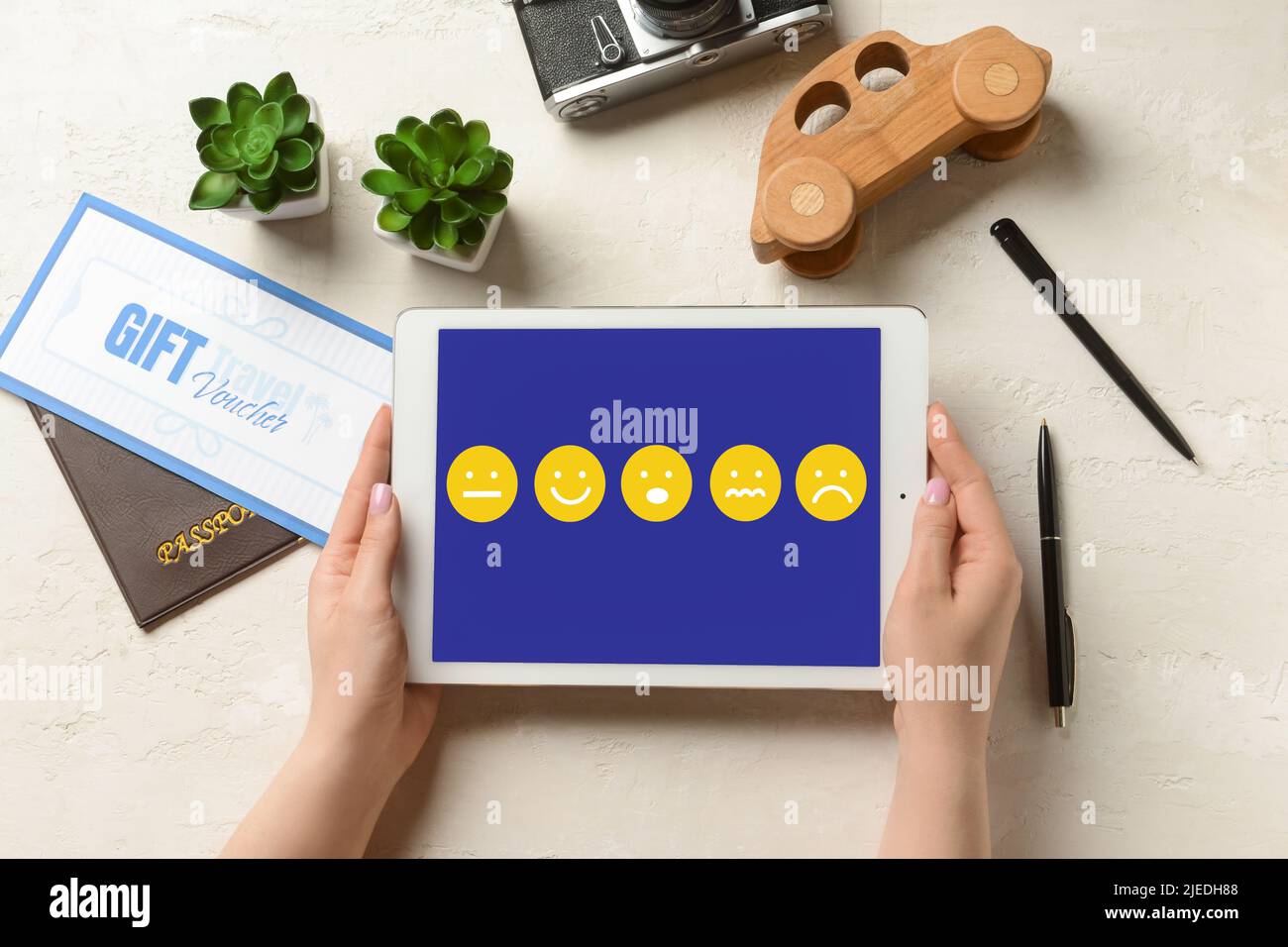 Female hands with travel accessories and tablet computer with emoticons ...