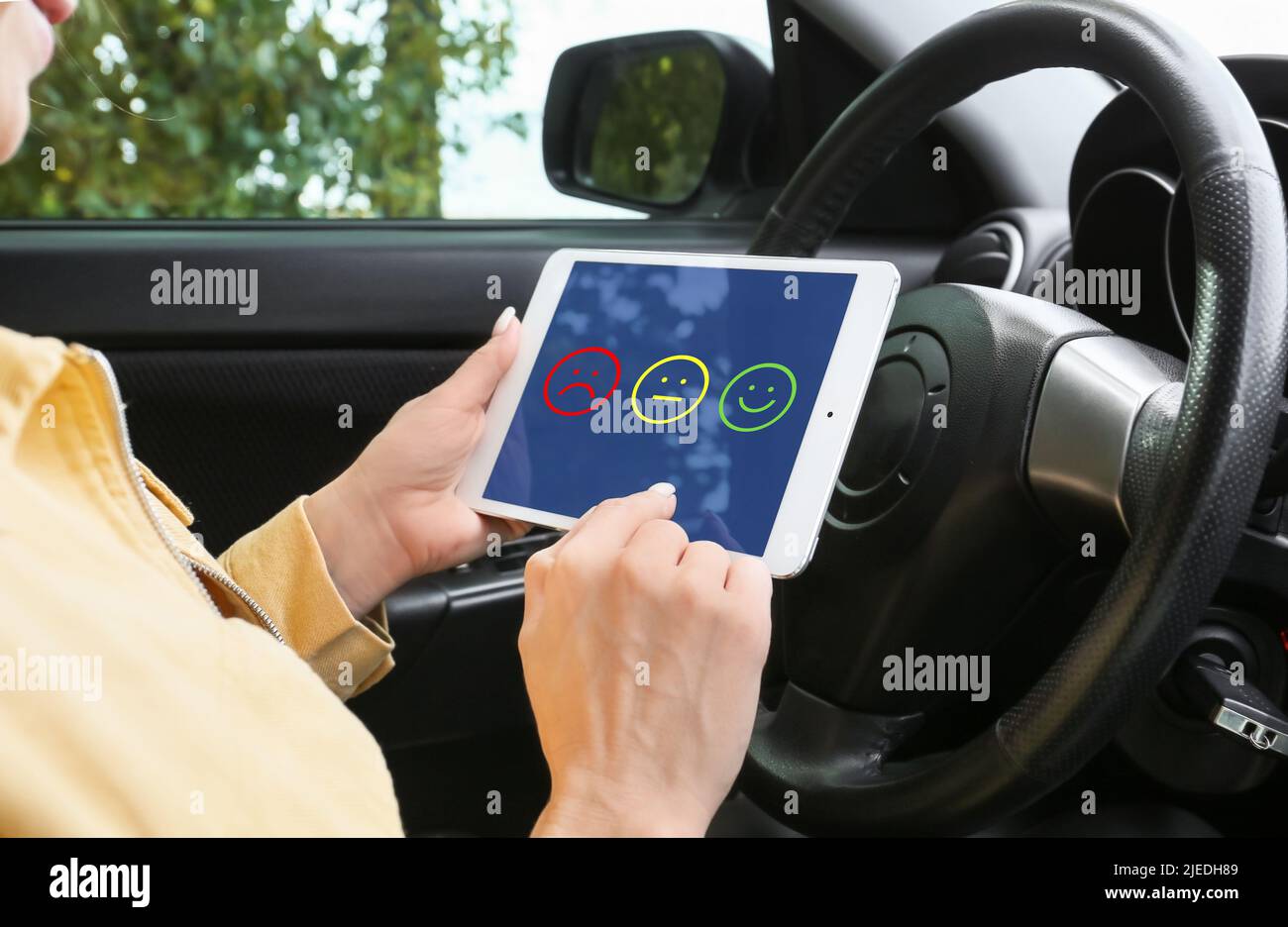 Female driver using tablet computer with emoticons on screen Stock ...