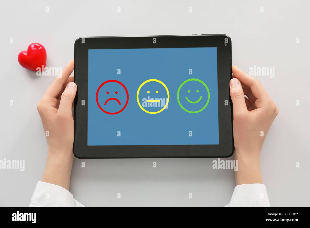 Female hands holding tablet computer with emoticons on screen against ...