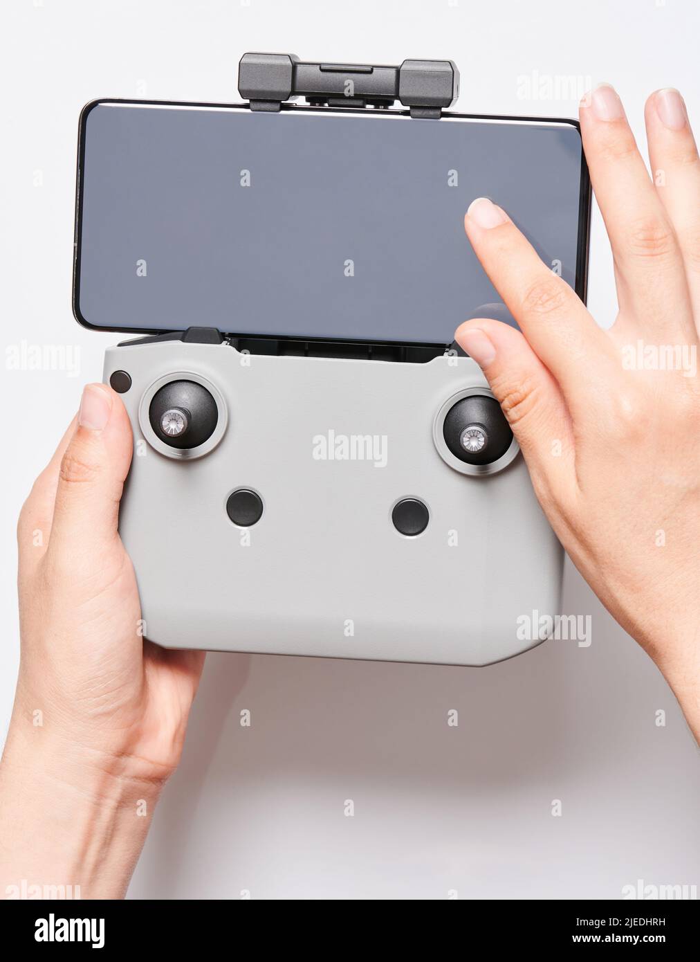 Using remote control with smartphone in hand isolated on studio ...