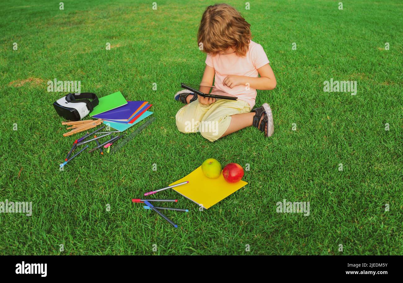 Kid with tablet sit on grass in park. Kids education, learning and ...