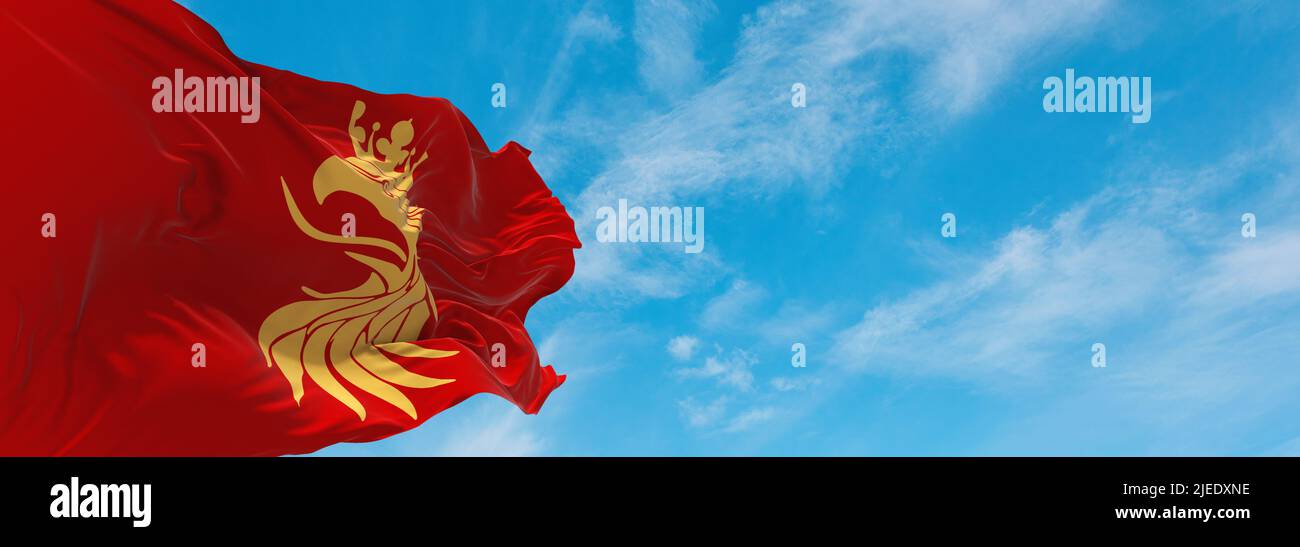official flag of Skane , Sweden at cloudy sky background on sunset ...