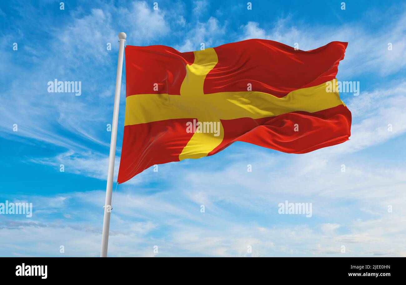 official flag of Skanska , Sweden at cloudy sky background on sunset ...