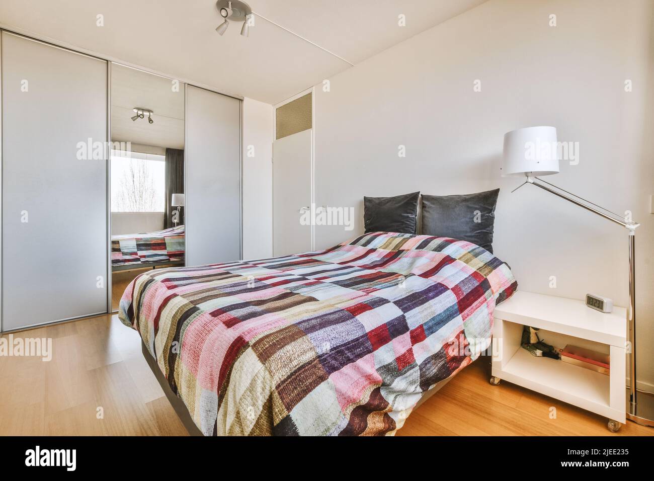 A comfortable bed with a decorative blanket, a bedside table with a ...