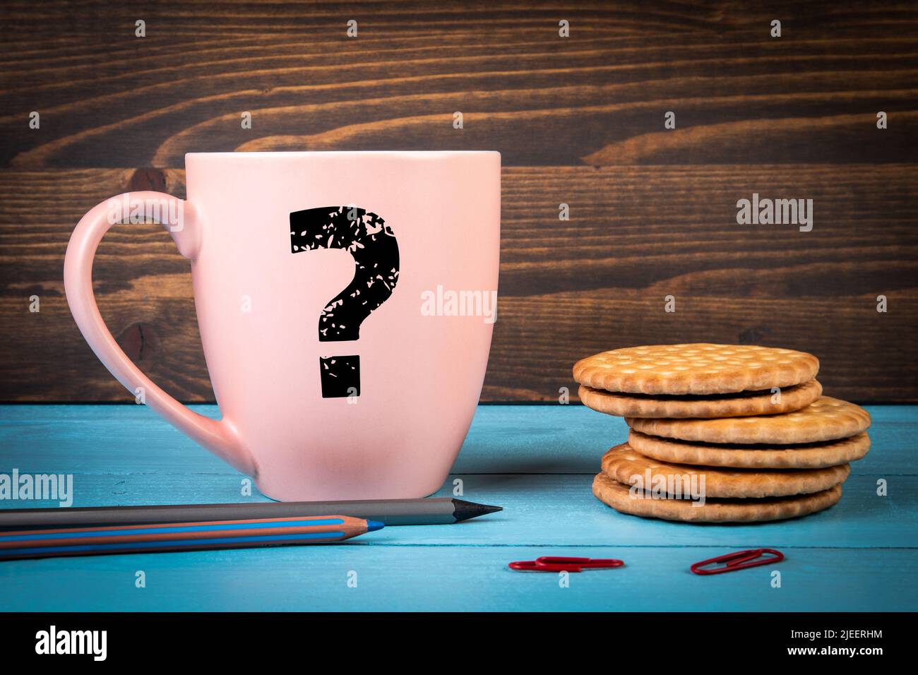 Question mark on a pink coffee mug. Blue and black wooden background ...