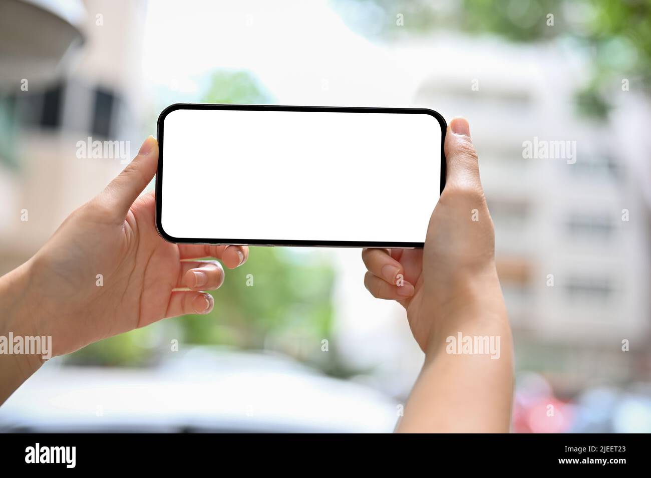 A female hands holding a smartphone white screen mockup over blurred ...