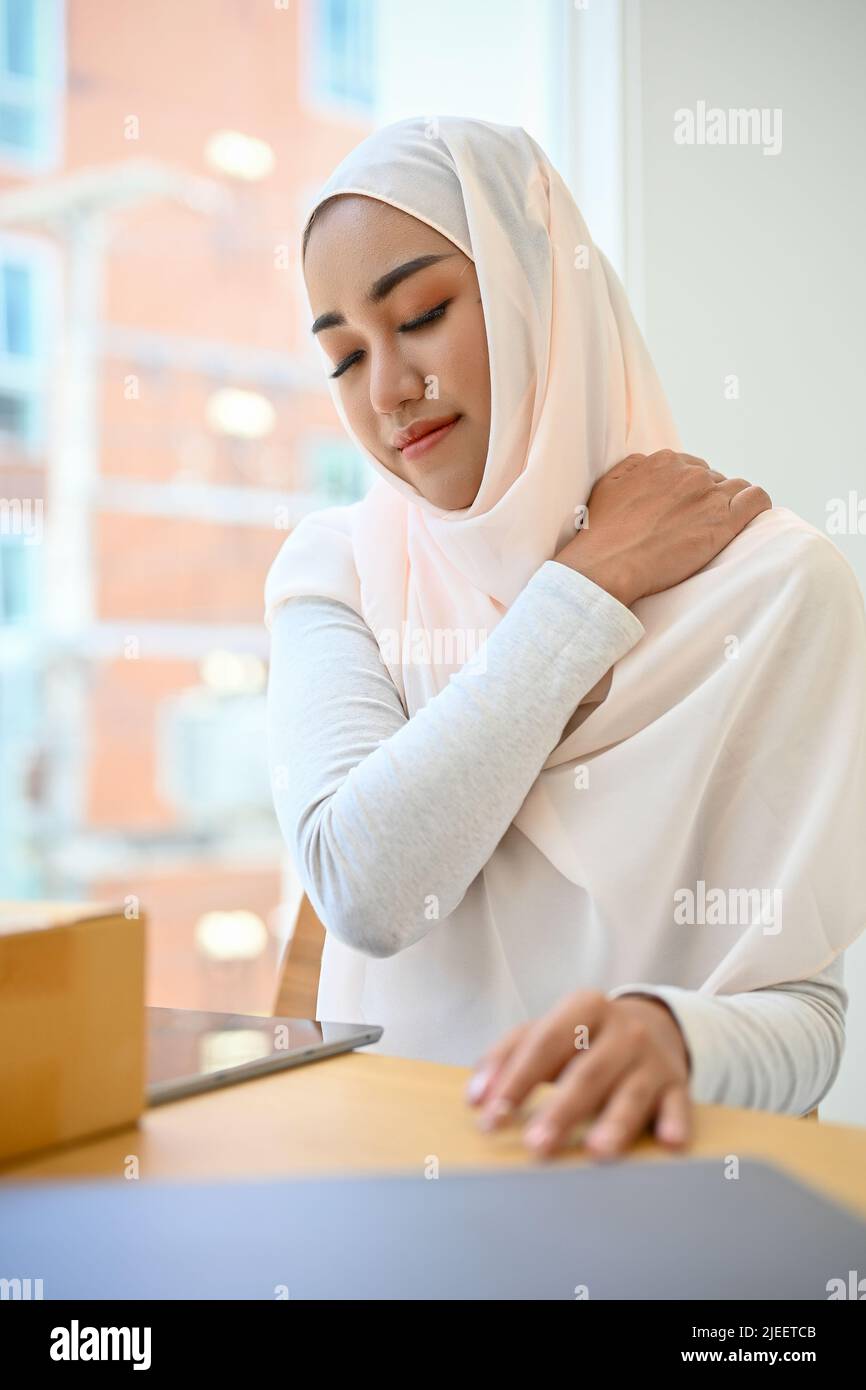 Tired young asian muslim businesswoman or female worker suffering from ...