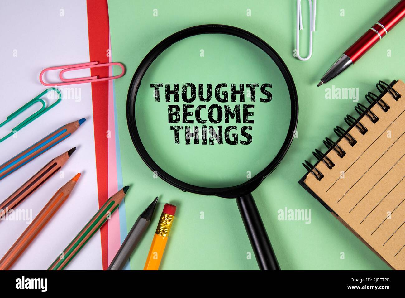 Thoughts become things. Text and magnifying glass on a green paper ...