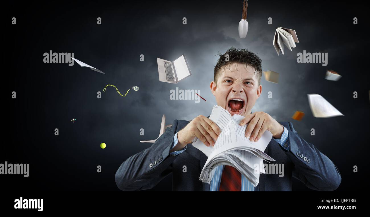 Young stressed man ripping documents with frustrated facial expression ...