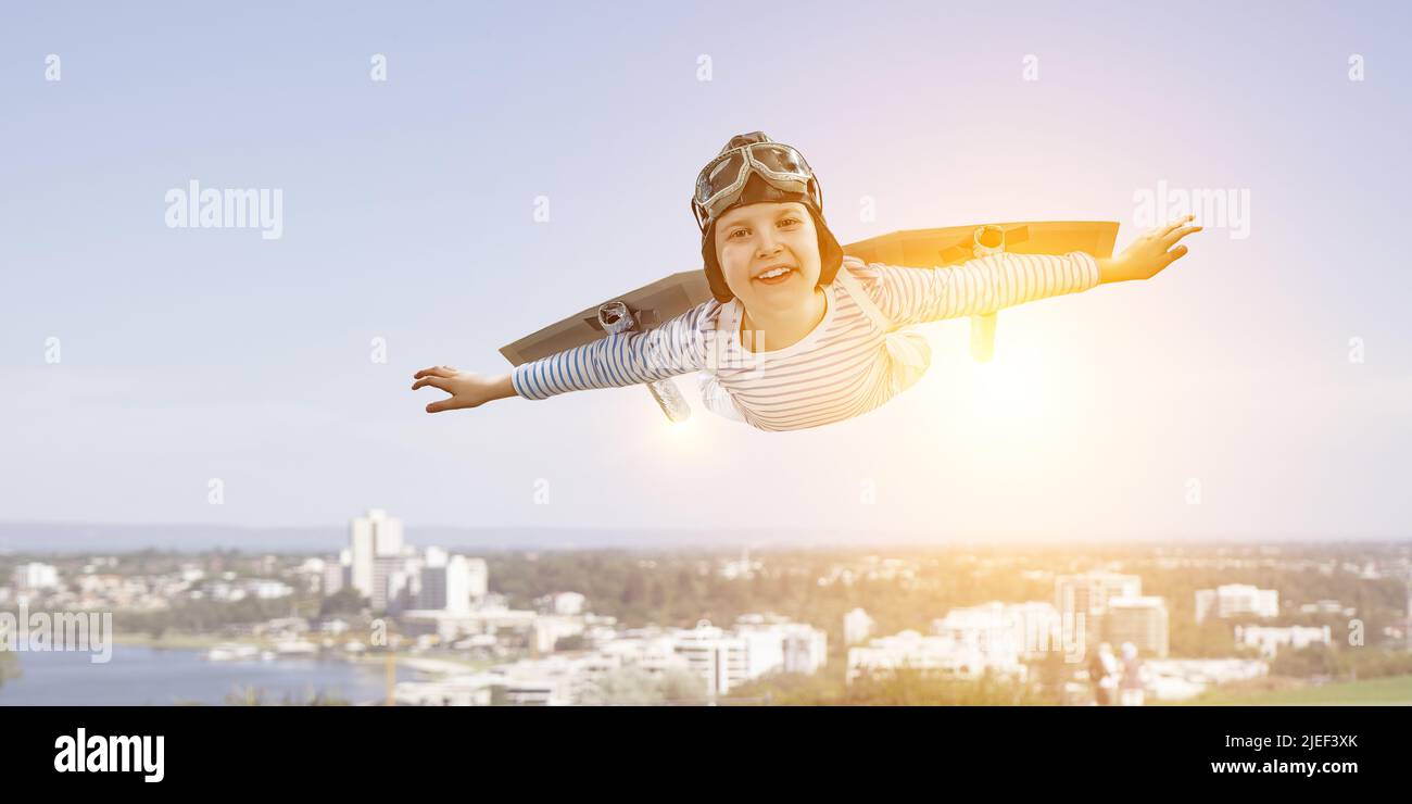 Happy little boy flying wearing helmet Stock Photo - Alamy