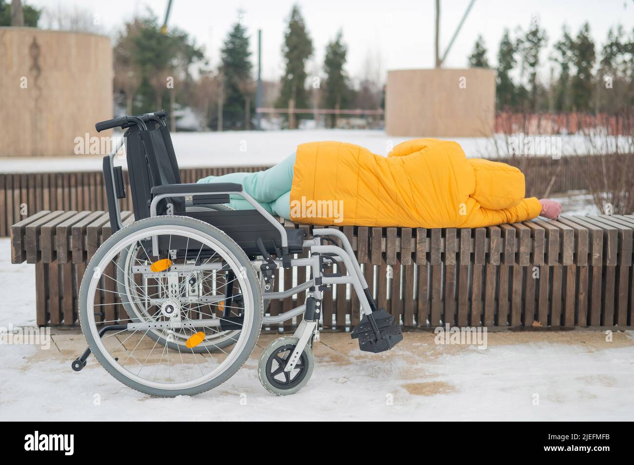 Homeless woman sleeping on a park bench next to a wheelchair Stock ...