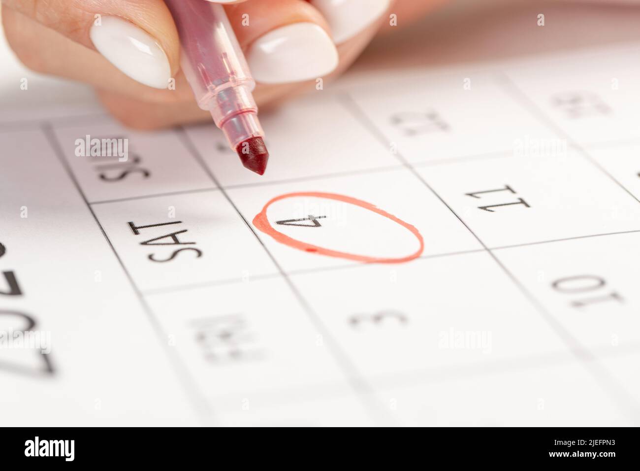 female hand marks with a red marker in the calendar notes an important ...