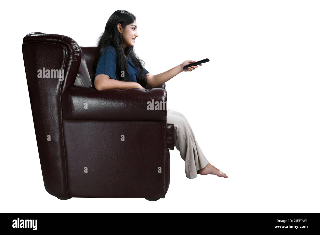 Asian woman holding a television remote while sitting on the couch ...