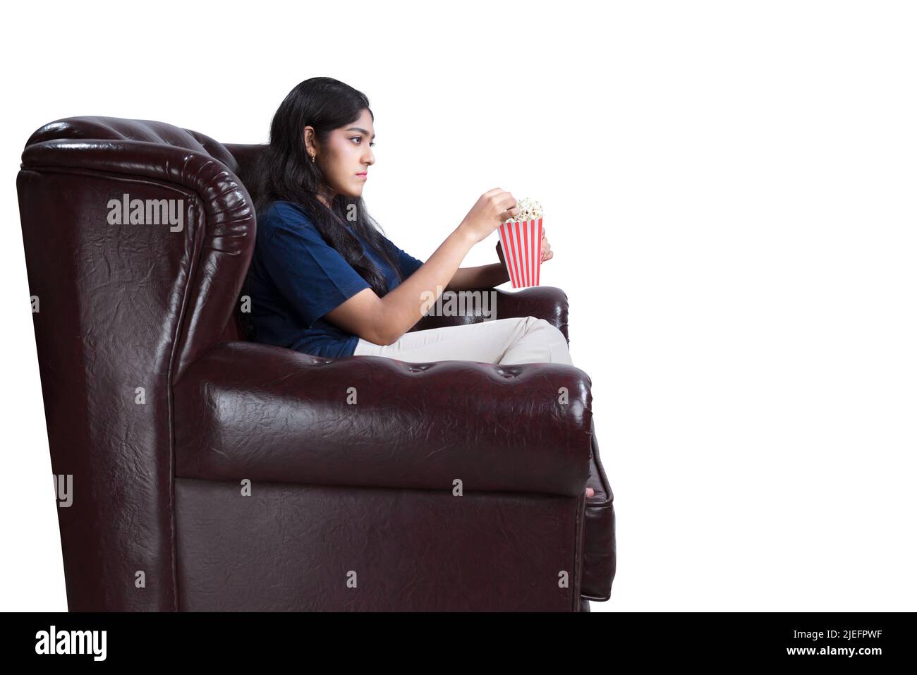 Asian woman holding a popcorn sitting on the couch isolated over white ...