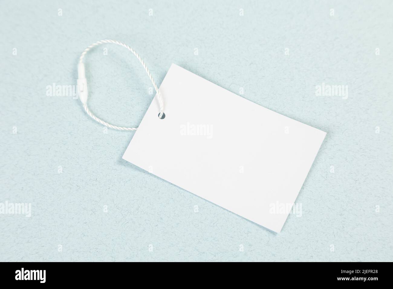 An empty white price tag lies on a gray-blue background with a soft ...