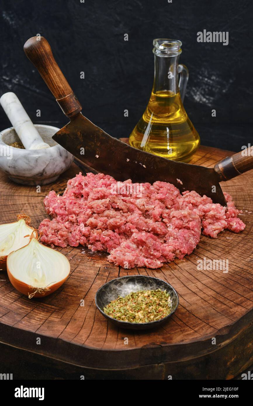 Making fresh raw minced meat with vintage chopping knife on wooden log ...