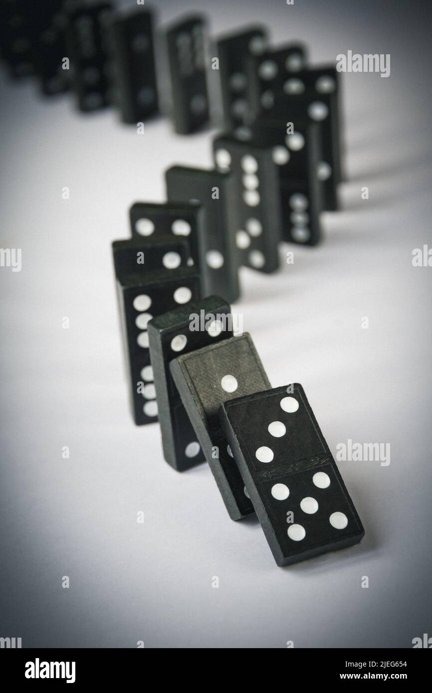 Black dominoes chain on a white table background. Domino effect concept ...