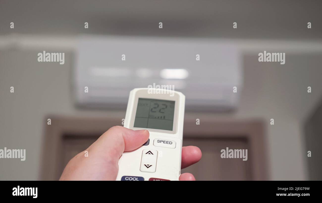 Hand with remote control turns on white air conditioner Stock Photo - Alamy