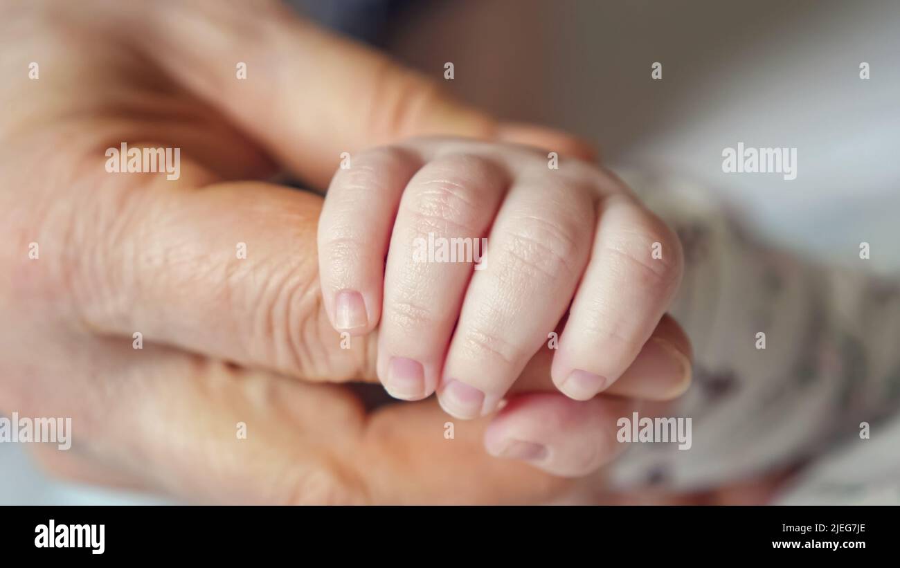 Mother holds tiny hand of newborn baby girl in bedroom Stock Photo - Alamy