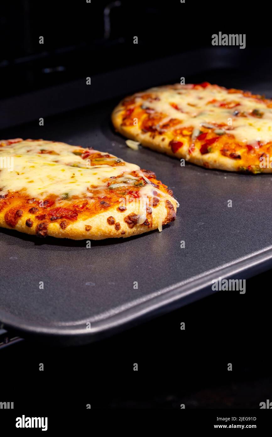Vegetable pizza with melted cheese cooked on a baking tray in an oven ...