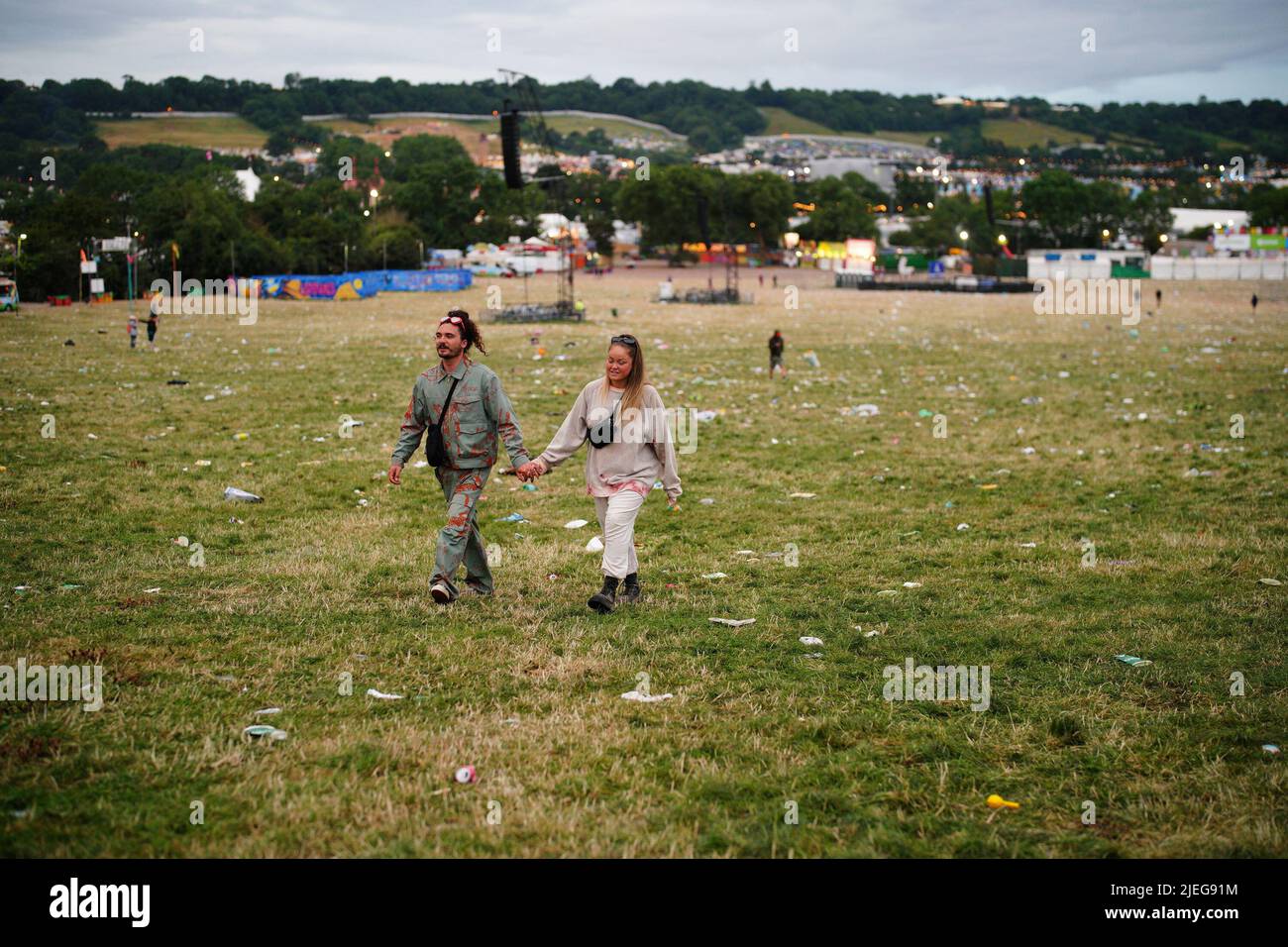 Festival goers walk amongst the waste left at Worthy Farm in Somerset ...