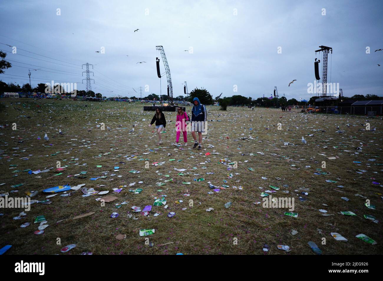 Festival goers walk amongst the waste left at Worthy Farm in Somerset ...