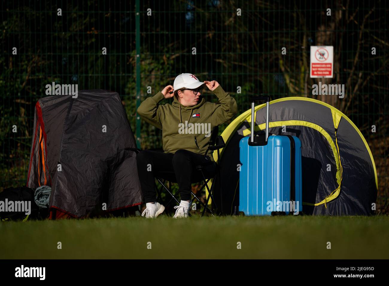 A person sits by their tent after camping overnight in the queue to ...