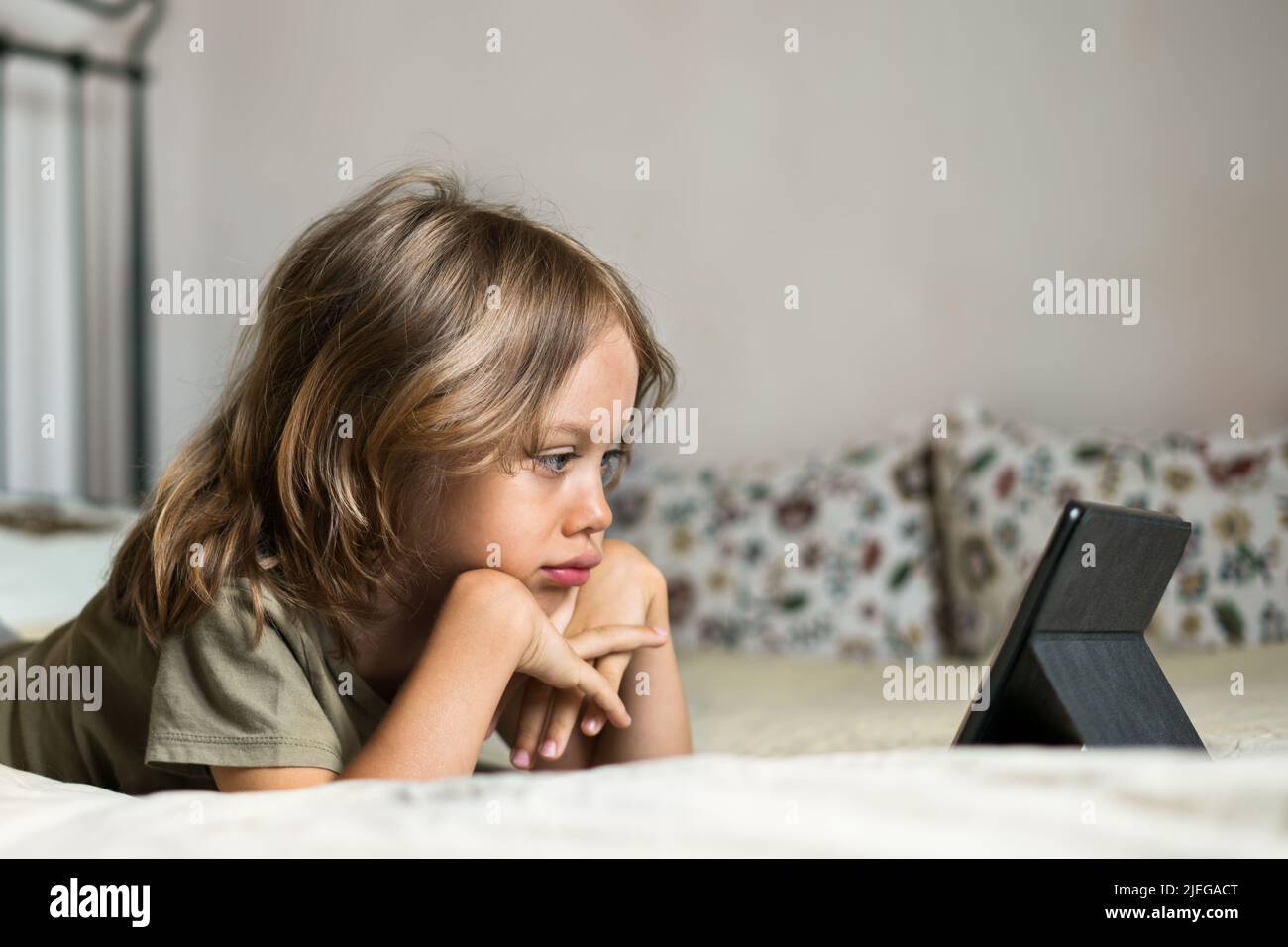 Boy lying on the bed using digital tablet computer playing games or ...