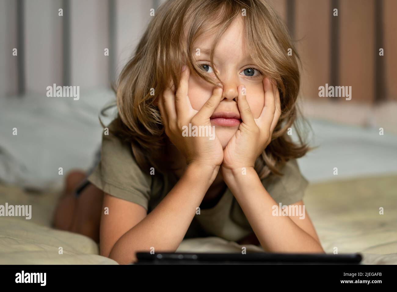 Boy lying on the bed using digital tablet computer playing games or ...