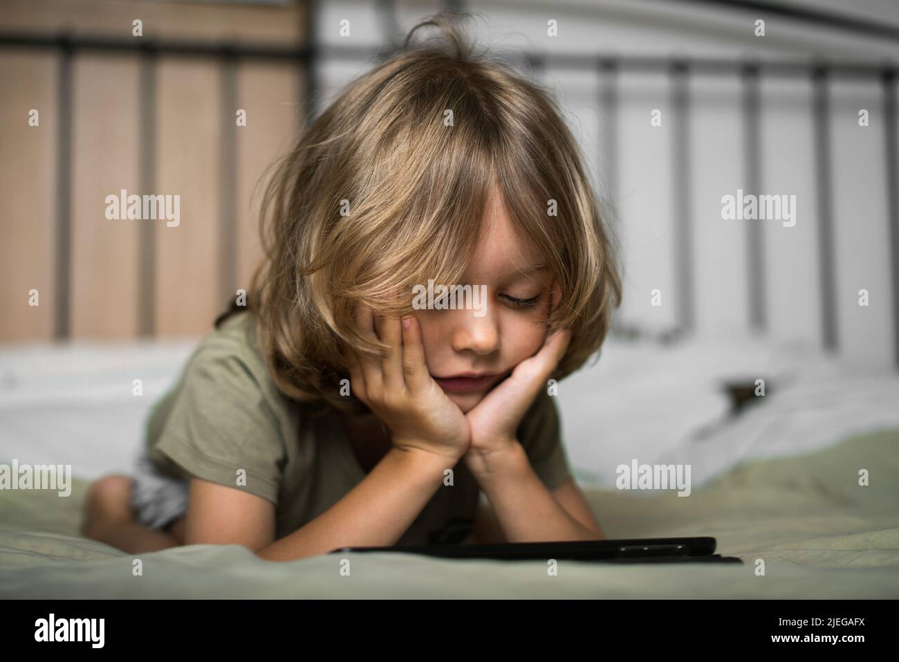 Boy lying on the bed using digital tablet computer playing games or ...