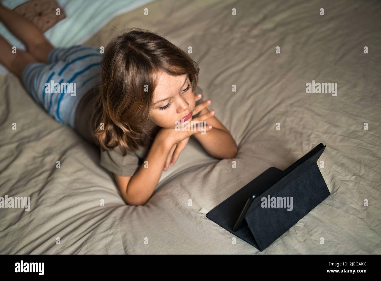 Boy lying on the bed using digital tablet computer playing games or ...