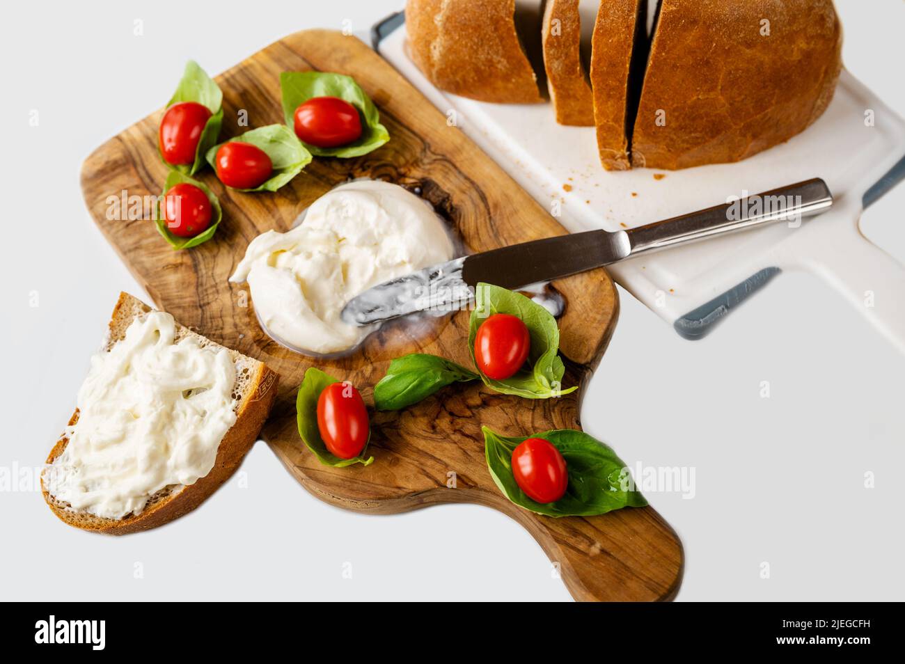 Cherry tomato on basil leaf, mozzarella cheese on wooden kitchen board ...
