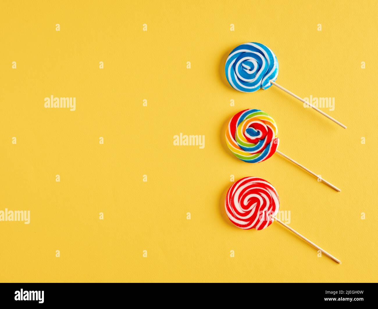 Colorful swirl round candy lollipops on yellow background Stock Photo ...