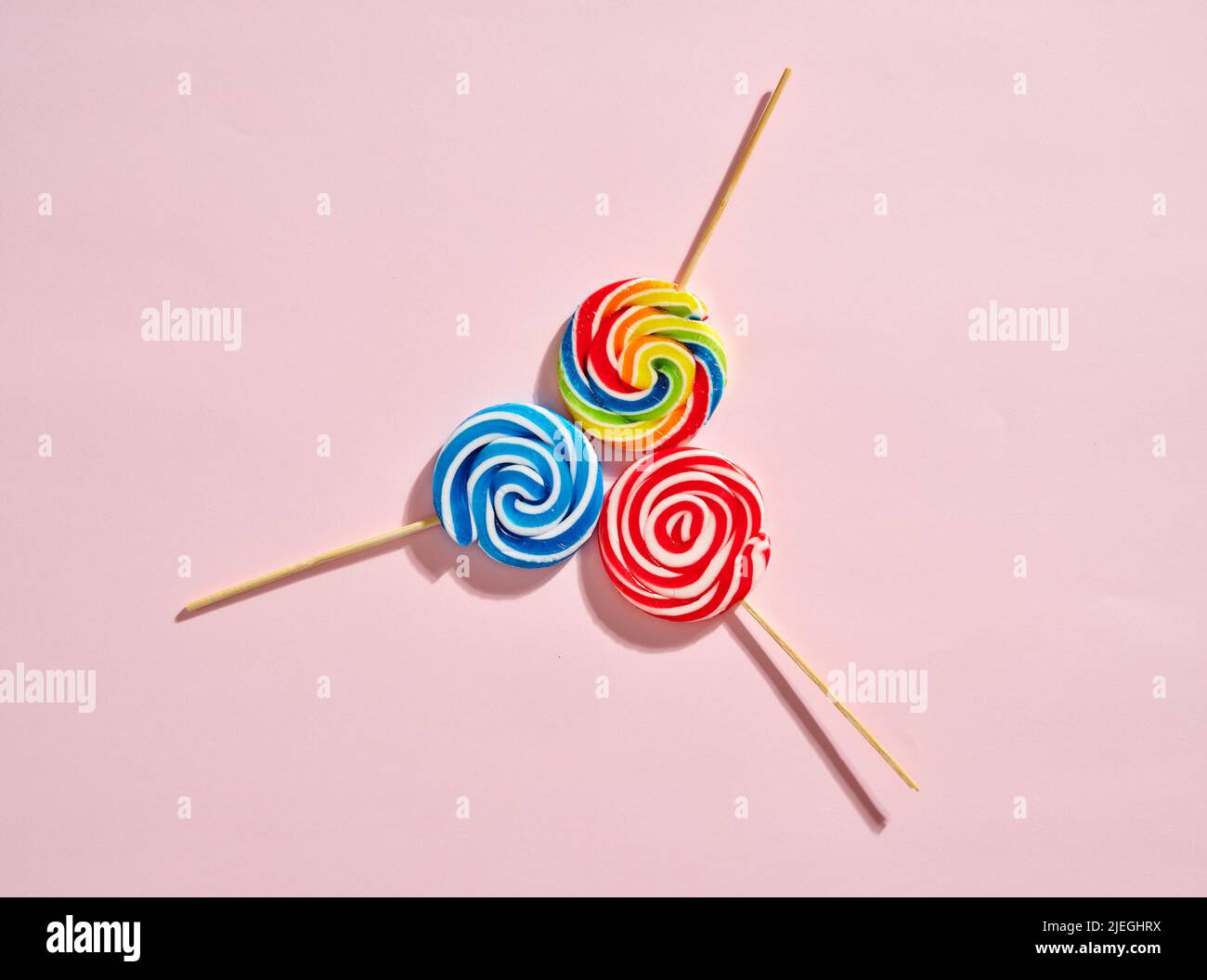 Colorful swirl round candy lollipops on pink background Stock Photo - Alamy